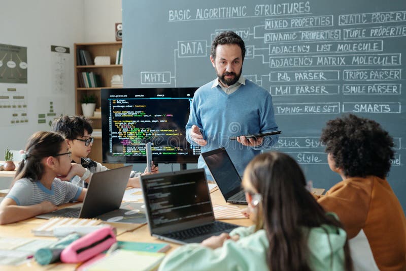 Teacher Guiding Students in Classroom with Computers Stock Image ...