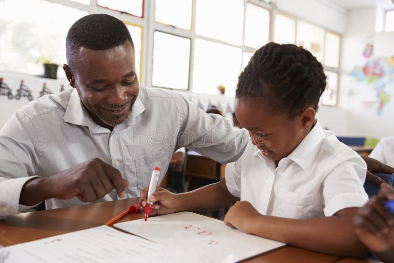 Teacher Helping Elementary School Girl at Her Desk, Close Up Stock ...