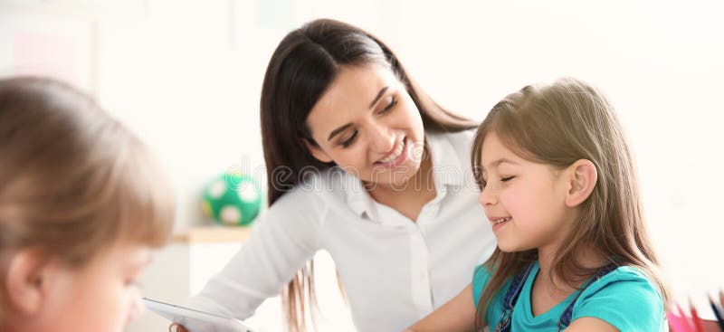 Teacher Helping Girl with Her Task in Classroom at School. Banner ...