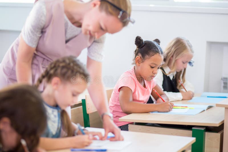 Teacher Helping Kids with Their Homework in Classroom at School Stock ...