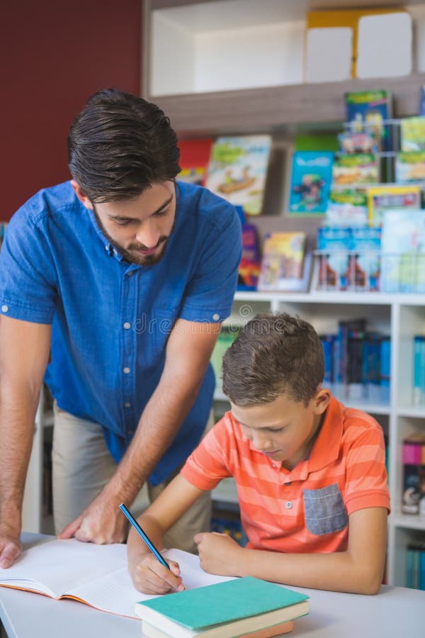 Teacher Helping School Kid with His Homework in Library Stock Photo ...