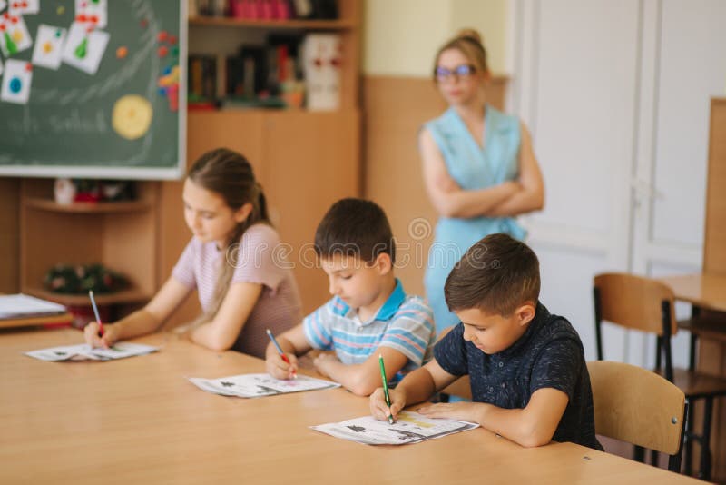 Teacher Helping School Kids Writing Test in Classroom. Education ...
