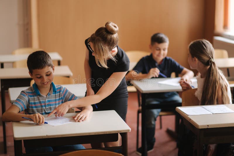 Teacher Helping School Kids Writing Test in Classroom. Education ...