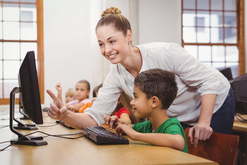 Teacher Helping Boy To Use Digital Tablet in Computer Class Stock Photo ...