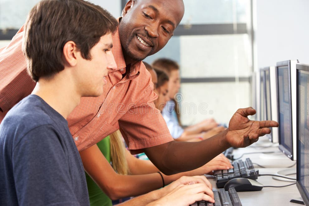 Teacher Helping Students Working at Computers in Classroom Stock Image ...