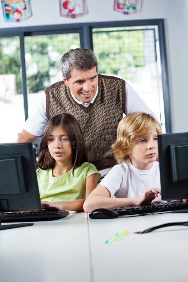 Teacher Looking at Schoolchildren Using Desktop Pc Stock Image - Image ...