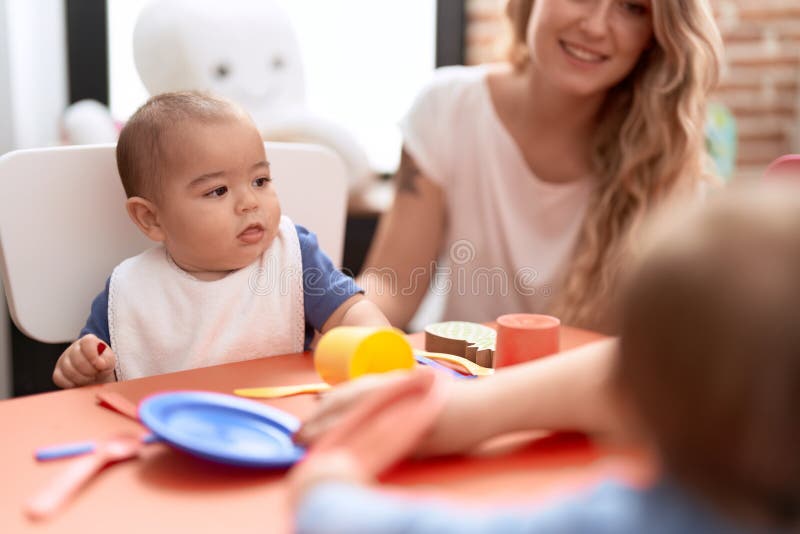 Teacher and Preschool Student Learning To Eat Sitting on Table at ...