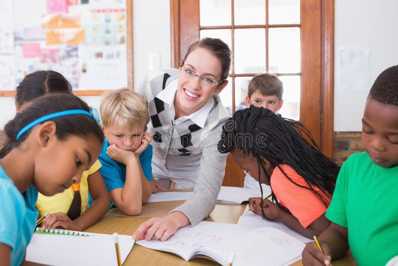 Teacher and Pupils Working at Desk Together Stock Image - Image of ...