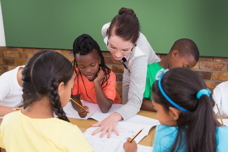 Teacher and Pupils Working at Desk Together Stock Image - Image of ...