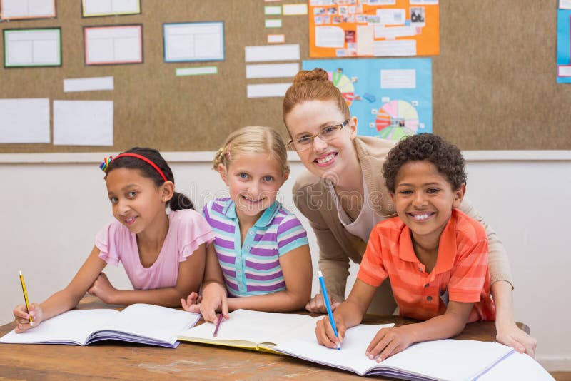 Teacher and Pupils Working at Desk Together Stock Photo - Image of ...
