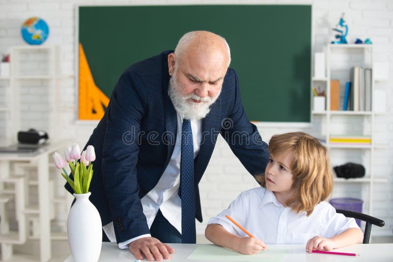 Teacher and School Boy. Elementary Pupil Reading and Writing with ...