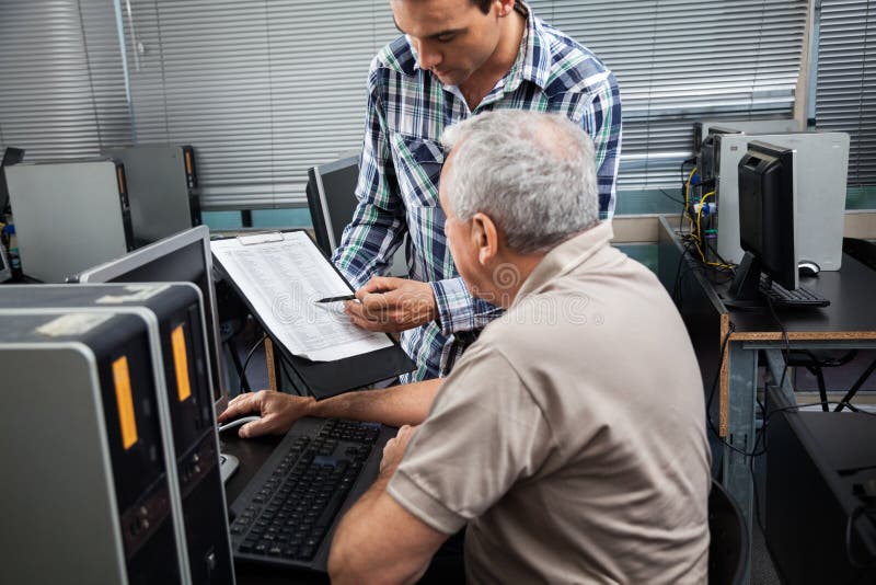 Teacher Showing Clipboard To Student in Computer Class Stock Photo ...