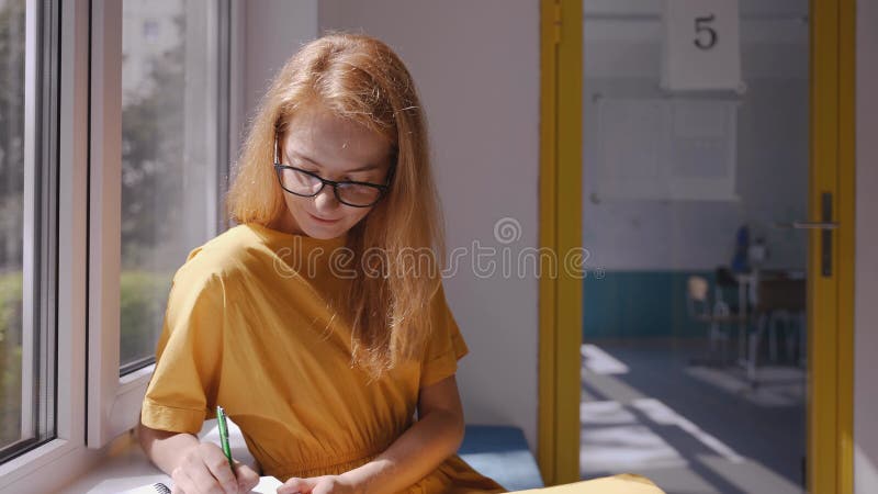 Teacher Sitting at School Window, Writing in Notebook and Smiling at ...