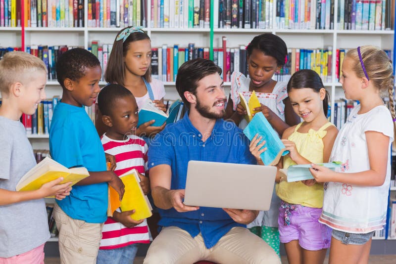Teacher Teaching Kids on Laptop in Library Stock Photo - Image of ...