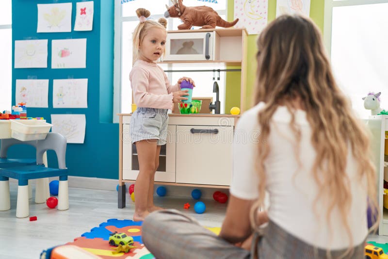 Teacher and Toddler Playing with Play Kitchen Standing at Kindergarten ...