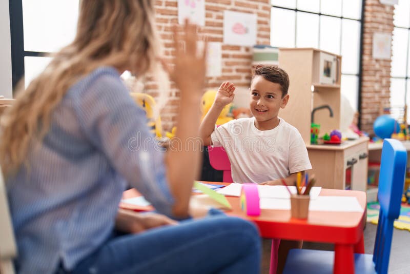Teacher and Toddler Sitting on Table High Five at Kindergarten Stock ...