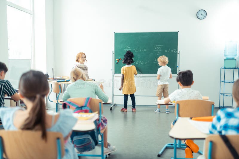 Teacher Watching Her Class while Two Kids Writing. Stock Photo - Image ...