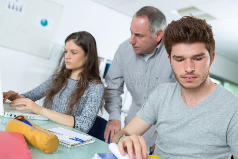 Teacher Watching Over Students at Work on Computers Stock Image - Image ...