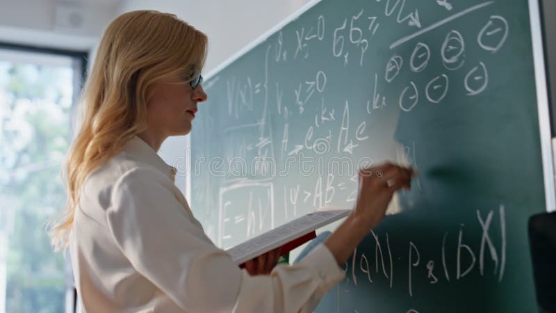 Teacher Writing Math Equations on Chalkboard Looking Book Closeup ...