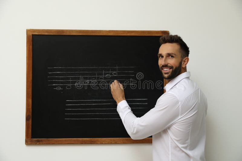 Teacher Writing Music Notes with Chalk on Blackboard in Classroom Stock ...