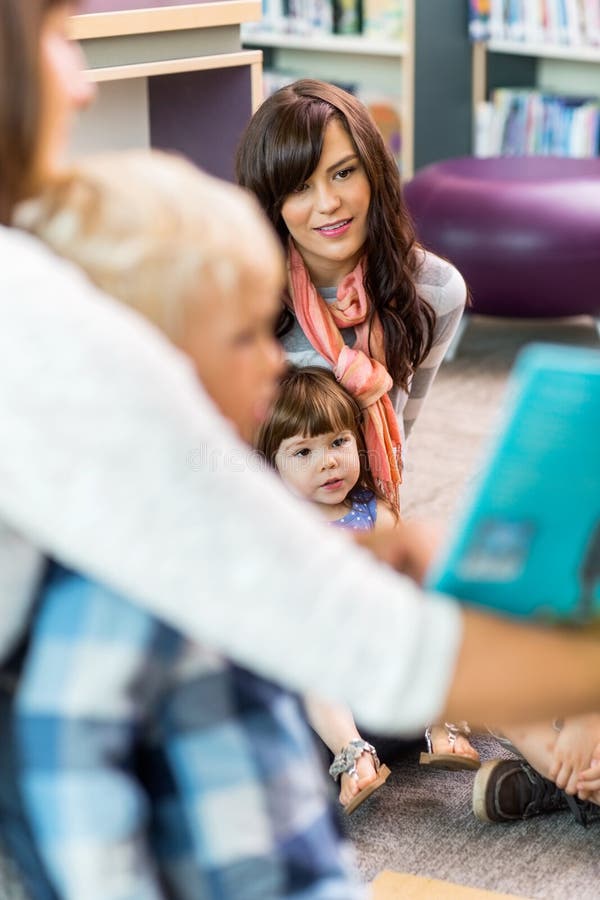Teacher Reading Book To Children in Library Stock Photo - Image of ...