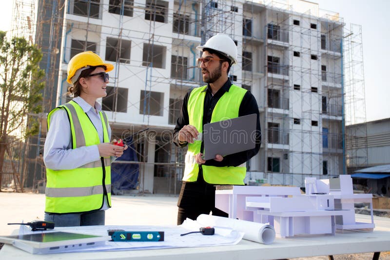 Team Architect and Builder Talking and Holding Laptop Looking Model House at Construction Site ...