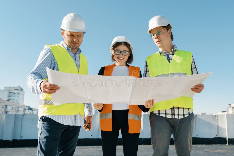 Team of Builders Engineers at a Construction Site, Reading Blueprint ...