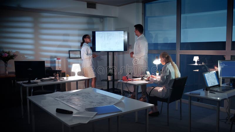 Team of Computer Engineers Discussing Something on a Big TV Screen in ...