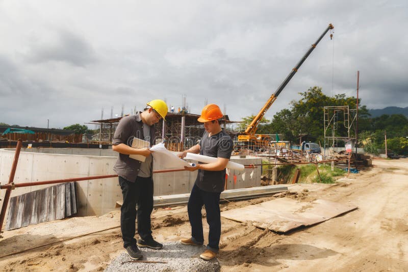 Team of Construction Workers Discussing Project Details with Blueprint in Construction Site ...