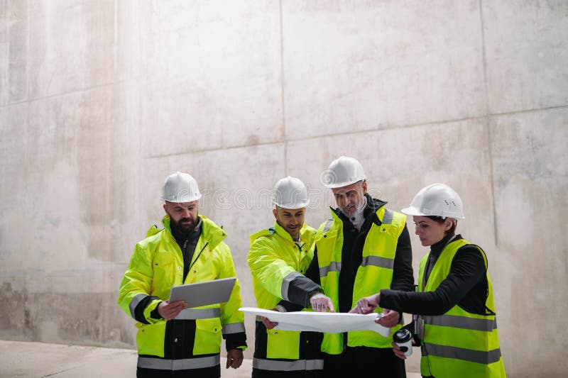 Team of Engineers and Construction Workers Reviewing Blueprints ...