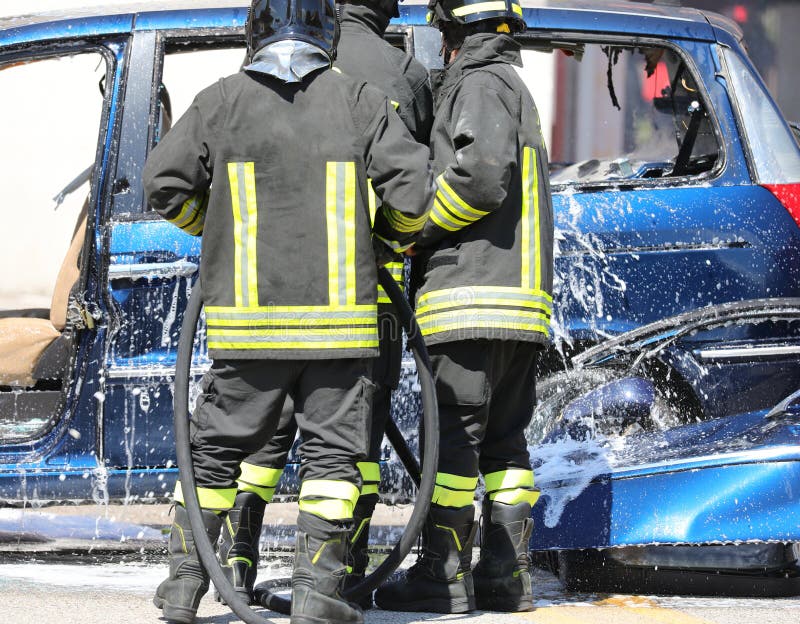 Team of Firefighters in Uniform Putting Out the Fire from a Car after a ...