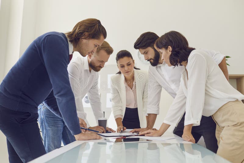 Team of Office Workers Together with Boss Leaning Over Table Studying ...