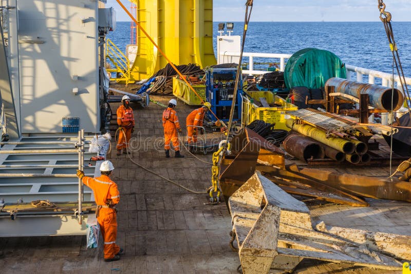 A Team of Rigger Lifting an Anchor from a Construction Work Barge ...