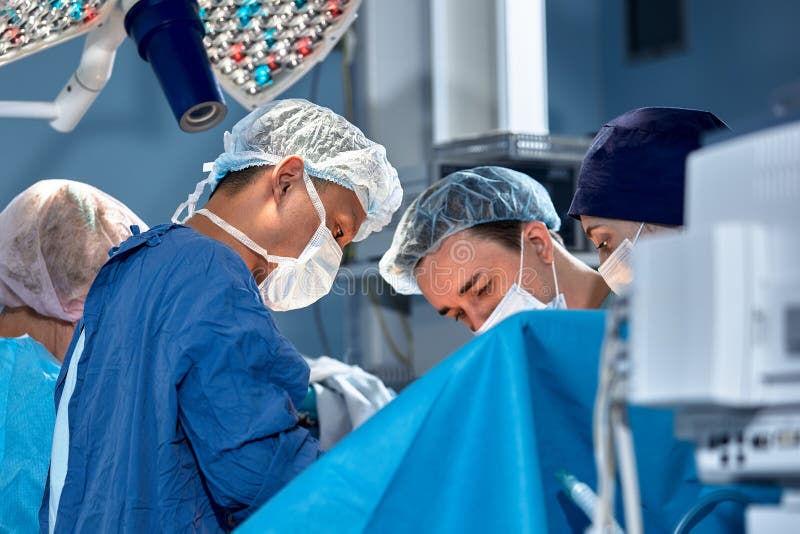 The Team of Surgeons in the Operating Room Bent Over the Patient ...