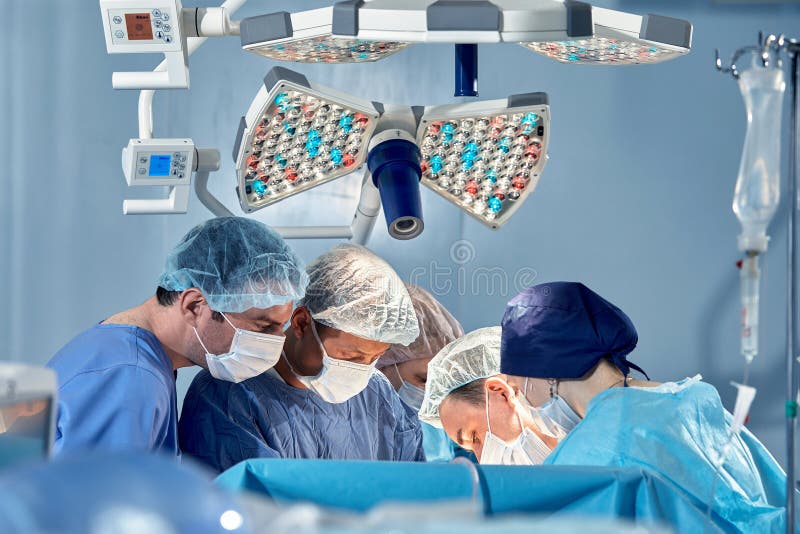 The Team of Surgeons in the Operating Room Bent Over the Patient ...