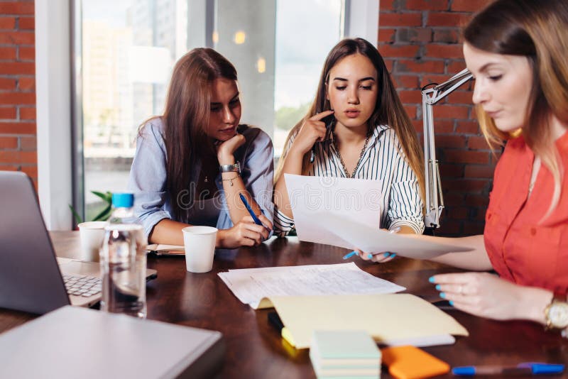 Team of Three Serious Female Colleagues Looking , Reading, Studying the ...