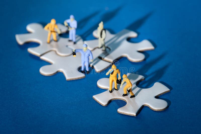Team of Tiny Worker Miniature Figures on Linked Jigsaw Puzzle Pieces ...