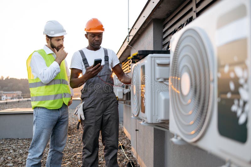 Two Technicians Standing with Multimeter Near Cooling System Stock ...