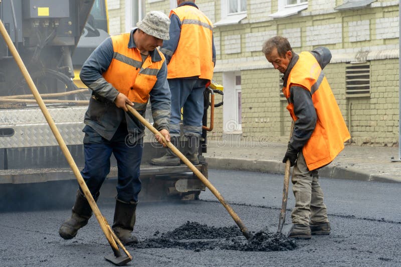 A Team of Workers with Shovels is Working on Laying New Asphalt. Road ...