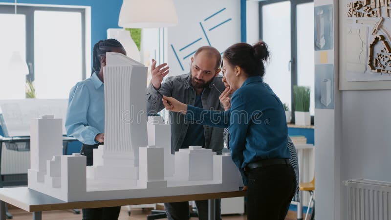 Team of Workmates Analyzing Building Model, Doing Teamwork on ...
