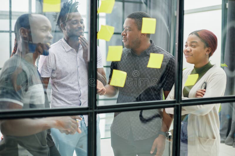 A Team of Young Designers Sticking Notes on Glass in a Modern Office ...