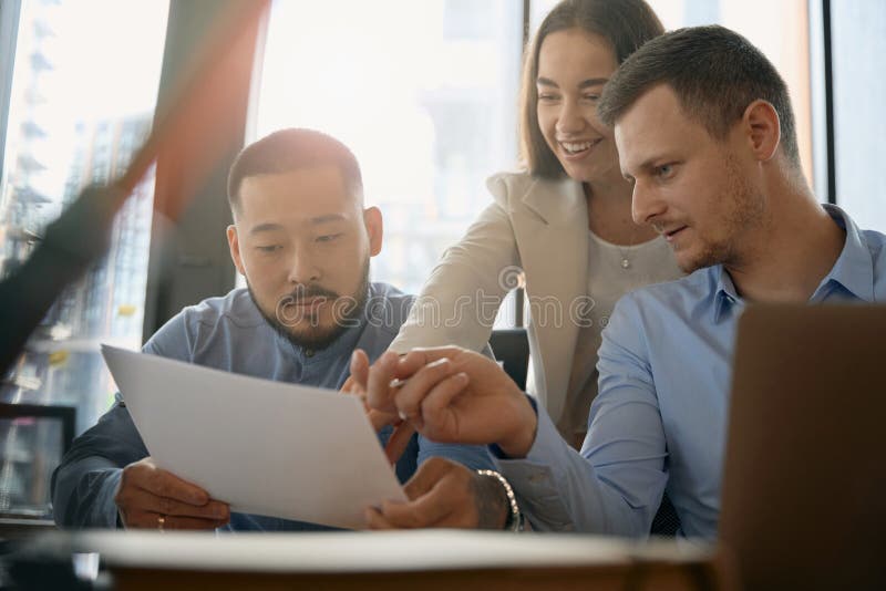 Team of Young Professionals Discussing Document in Open Office Stock ...