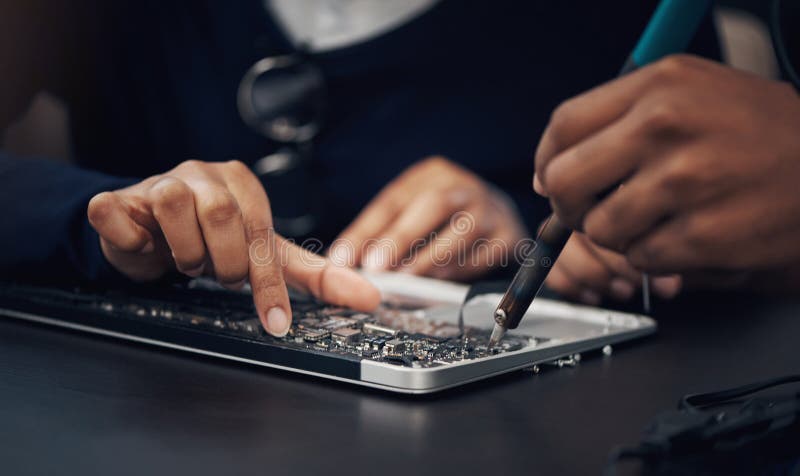 Teamwork Makes the Motherboard Work. Two Technicians Repairing a Laptop ...