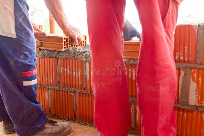 Team of Workers is Building Wall with Red Blocks and Mortar ...