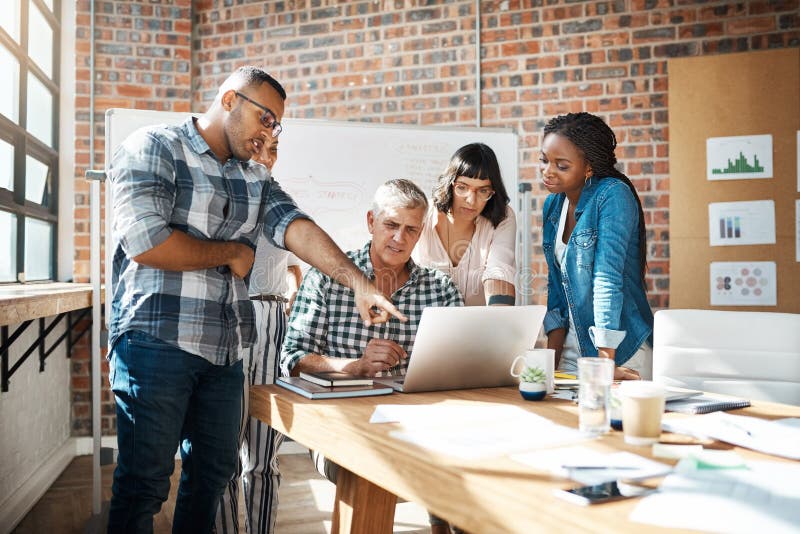 Teamwork Simplifies the Task. a Group of Colleagues Using a Laptop ...