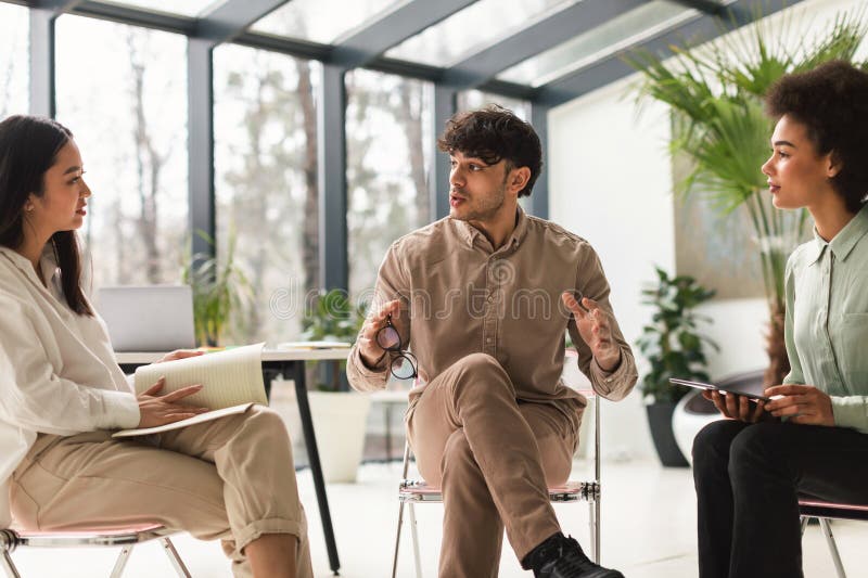 Young Multicultural Colleagues Trio Talking Discussing Startups in ...
