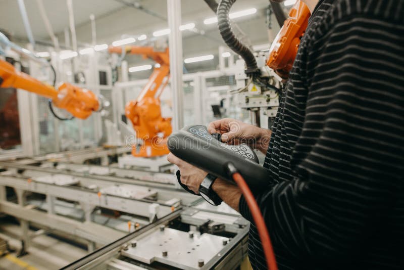 Technical Engineer Adjusting a Robotic Arm in the Industrial Automotive ...