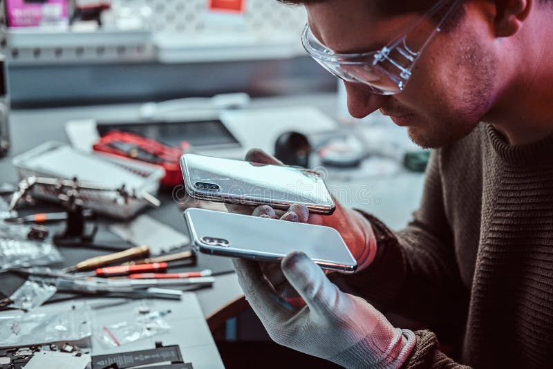 Technician Holds Two Identical Smartphones for Comparison, in One Hand ...