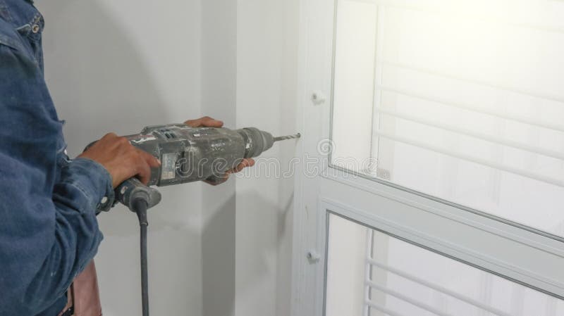 Technician Uses an Electrical Drilling Machine by Hand To Work at a ...