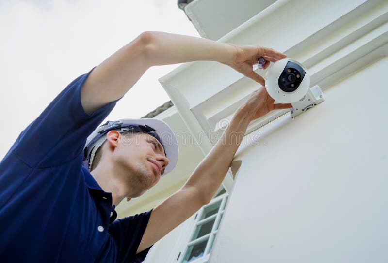 A Technician Installs a CCTV Camera on the Facade of a Residential ...